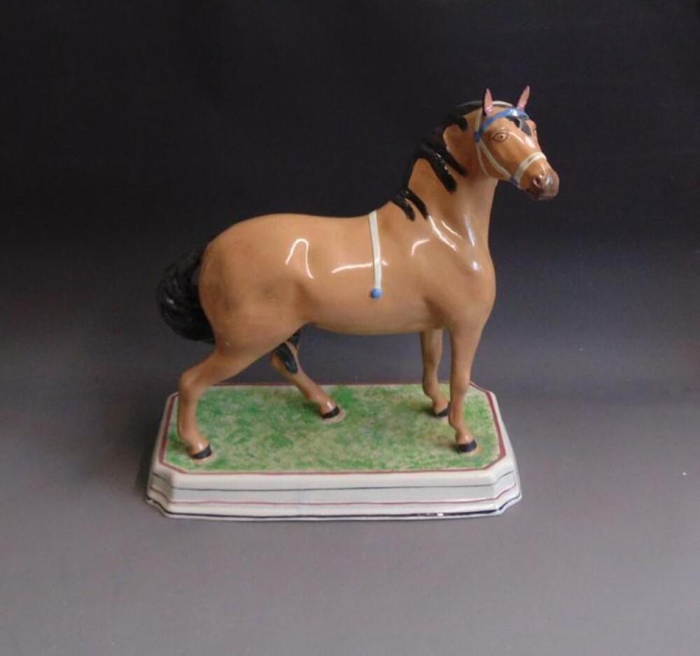 A rare large pottery pearlware model of a horse, standing on an oblong ...