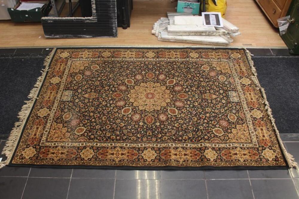 A machine made woollen rug, floral decoration on a navy blue ground ...