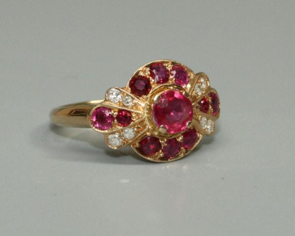 A ruby and diamond set unmarked rose gold ring, the round central claw ...