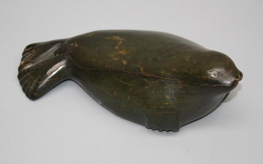 An Inuit stone carving of a rotund seal, incised marks to base, 22cm