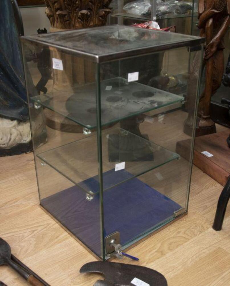 A small glass display case with two glass inside shelves with locking door