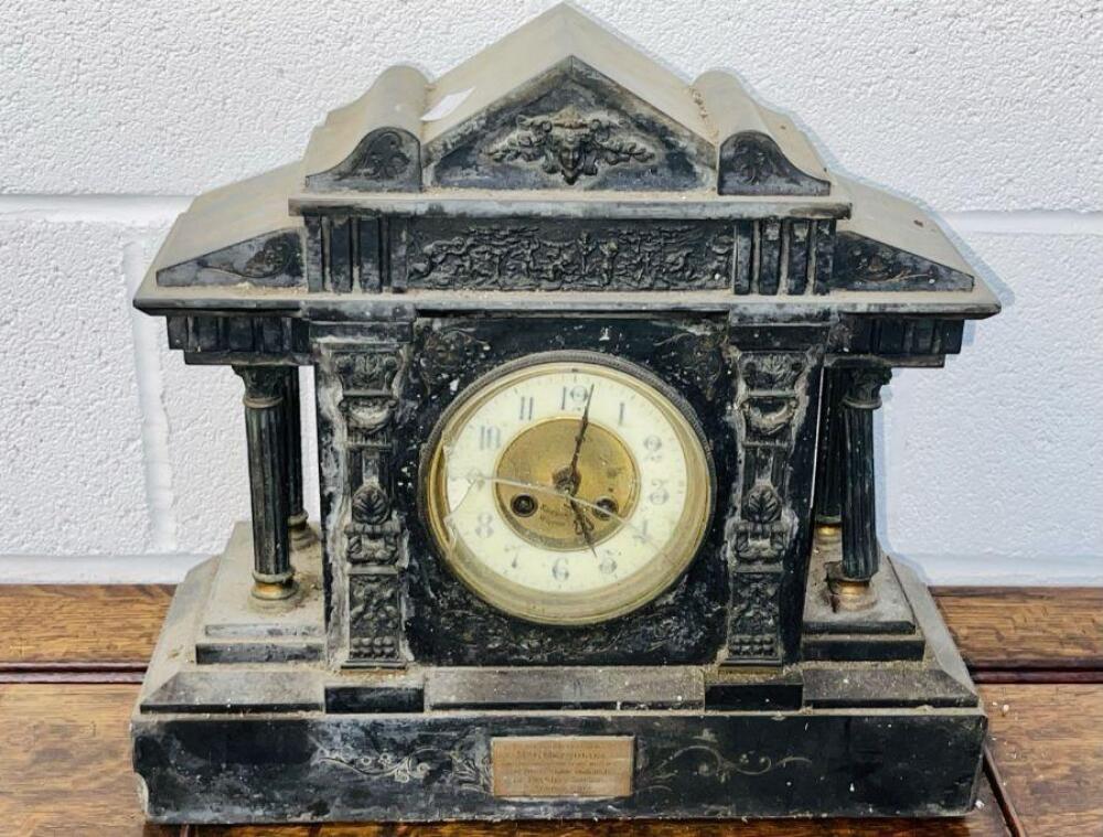 A slate mantle clock with brass enamel face and classical frieze