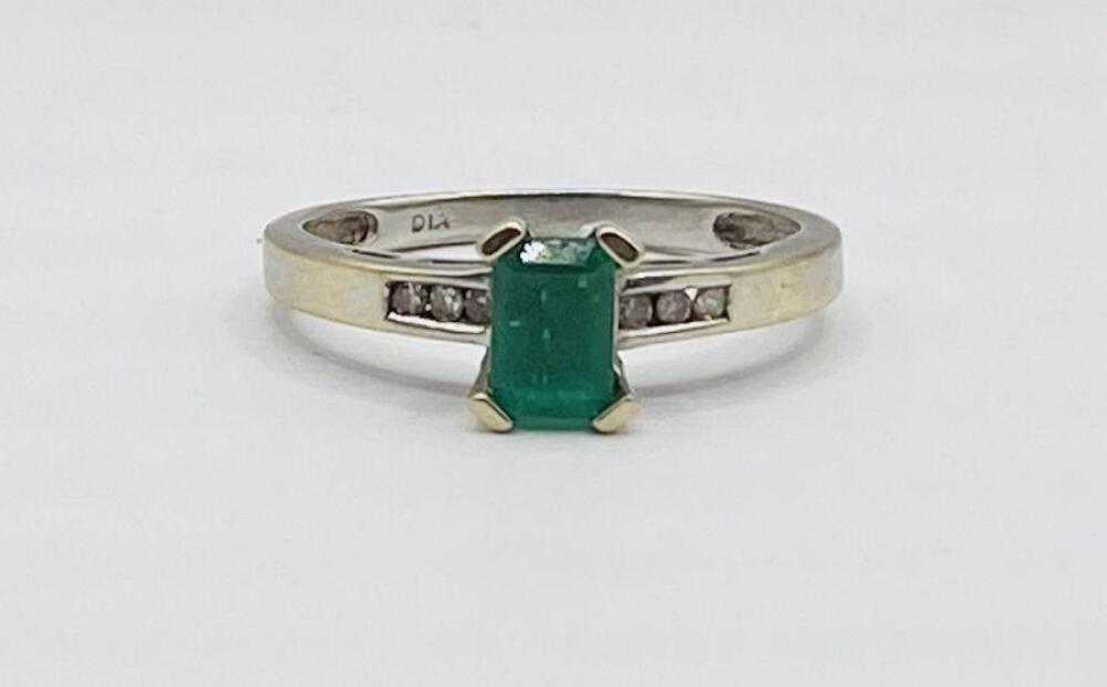 White metal ring, tests as 18ct gold. Emerald cut emerald, set with six ...
