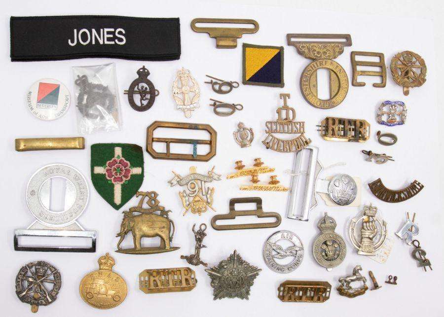 An assortment of British cap badges, buckles, shoulder titles and cloth ...