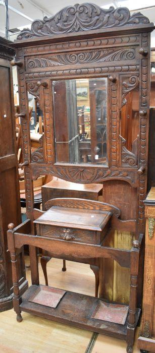 A 19th century carved oak hall robe with base drawer and top shelf ...