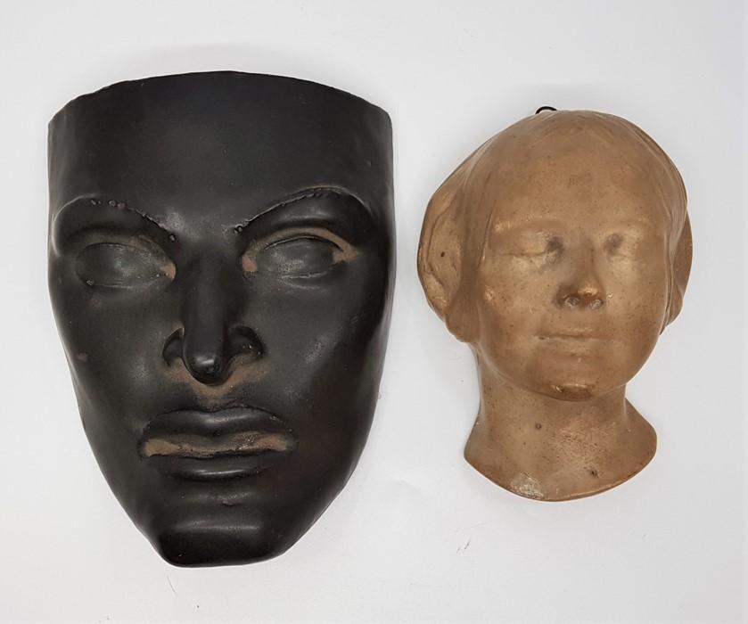 An Art Deco basalt mask together with similar. (2)