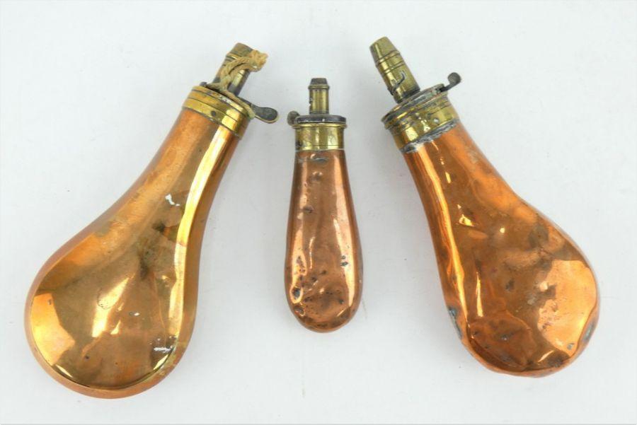 Two antique brass mounted copper powder flasks and a similar copper ...