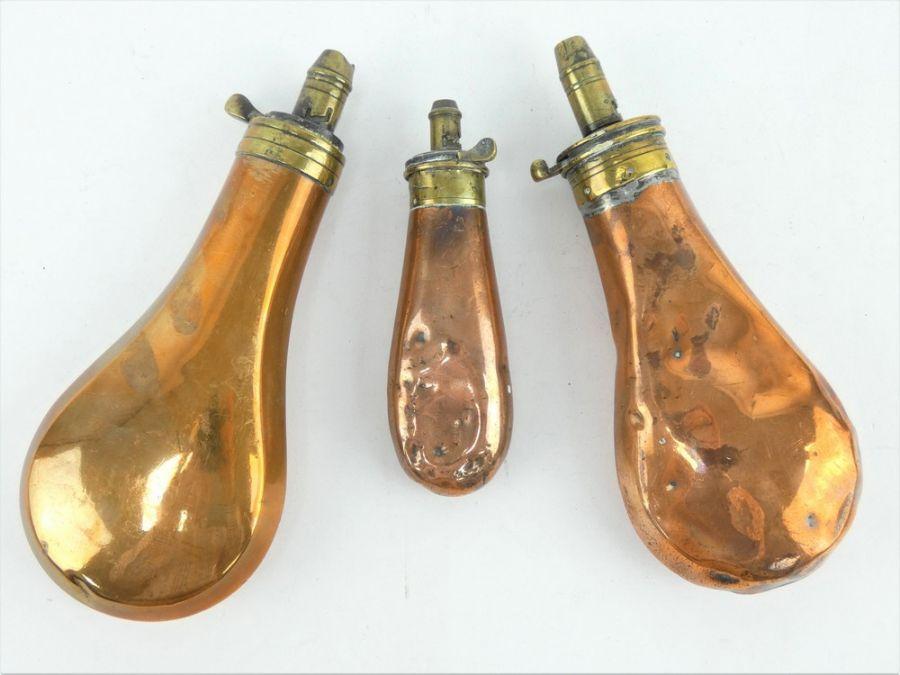 Two antique brass mounted copper powder flasks and a similar copper ...