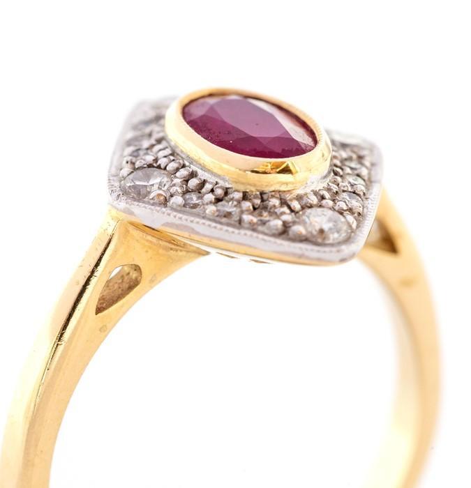 A ruby and diamond 18ct gold ring, the central oval rub over set ruby ...