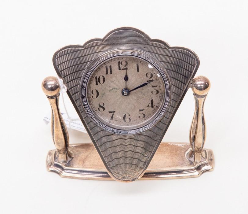 A silver table clock with engine turned detail on face, on swivel stand ...
