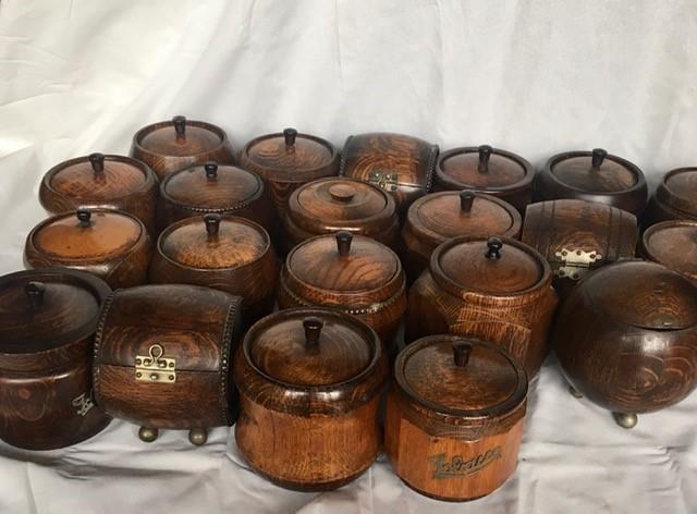 A large collection of various treen barrel form tobacco jars