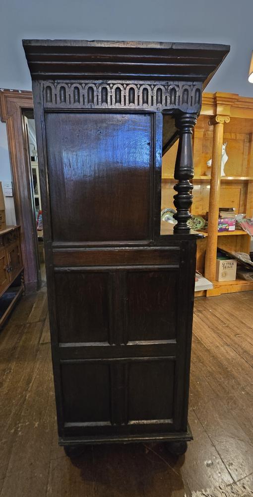 A carved Oak court cupboard. With moulded pediment, projecting frieze ...