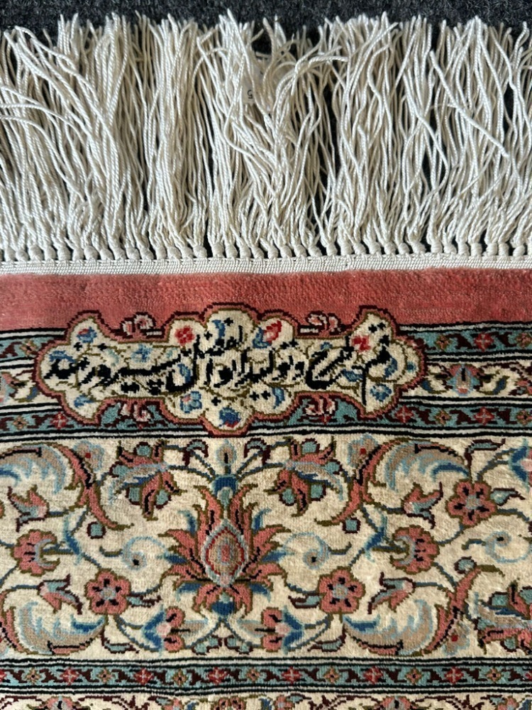 A Persian fine silk rug, signed Islamic calligraphy cartouche, the pink ...