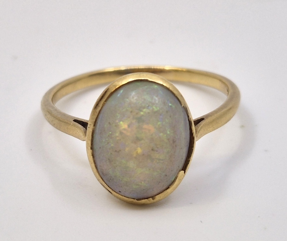 An 18ct. gold and opal ring, rub-over set single oval cabochon opal ...