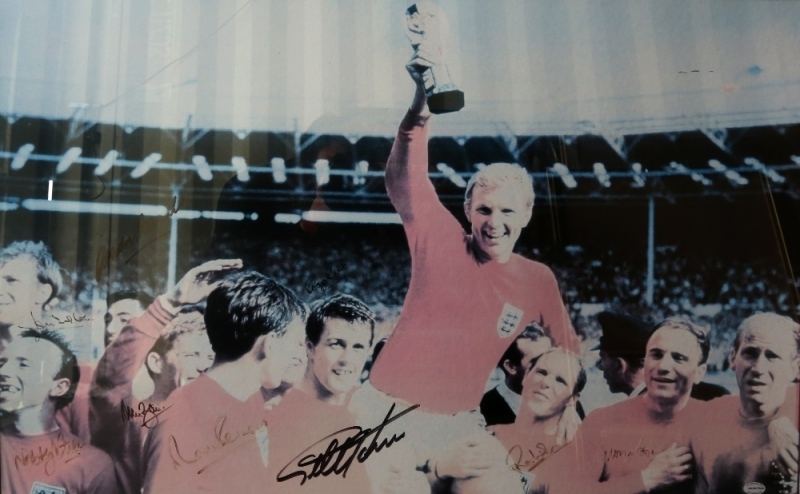 1966 World Cup; a framed colour photograph of Bobby Moore holding aloft ...