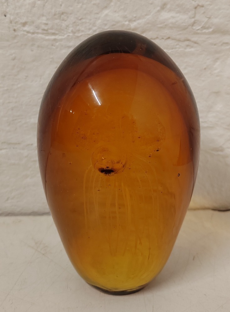 A 20th century amber glass dump paperweight with jellyfish shaped inclusion