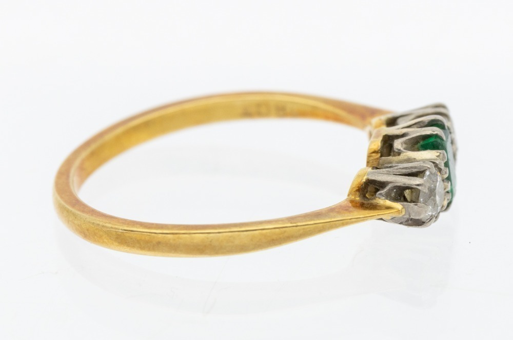 An emerald and diamond 18ct gold three stone ring, comprising a ...